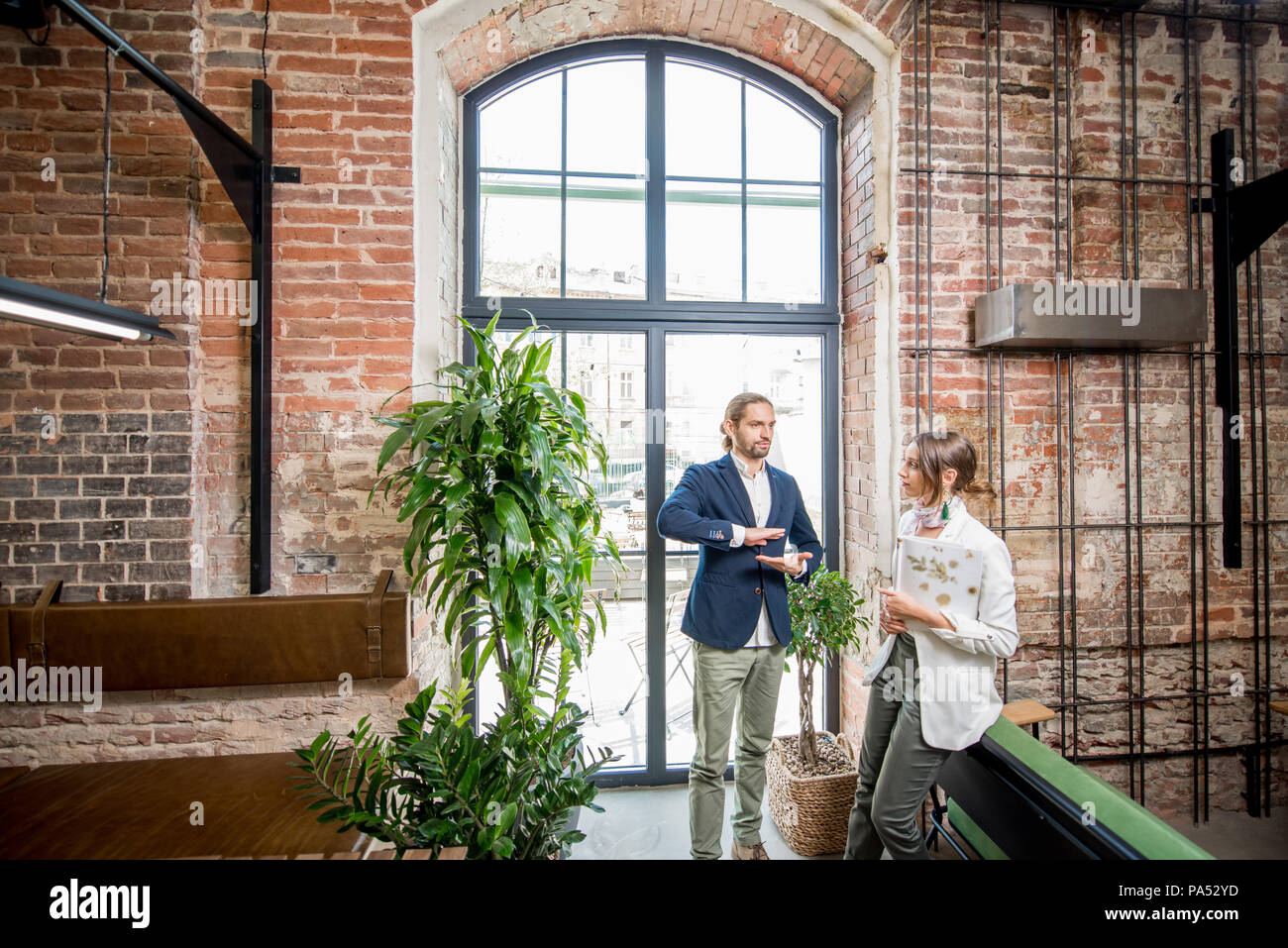 Business people having a conversation standing near the window in the ...