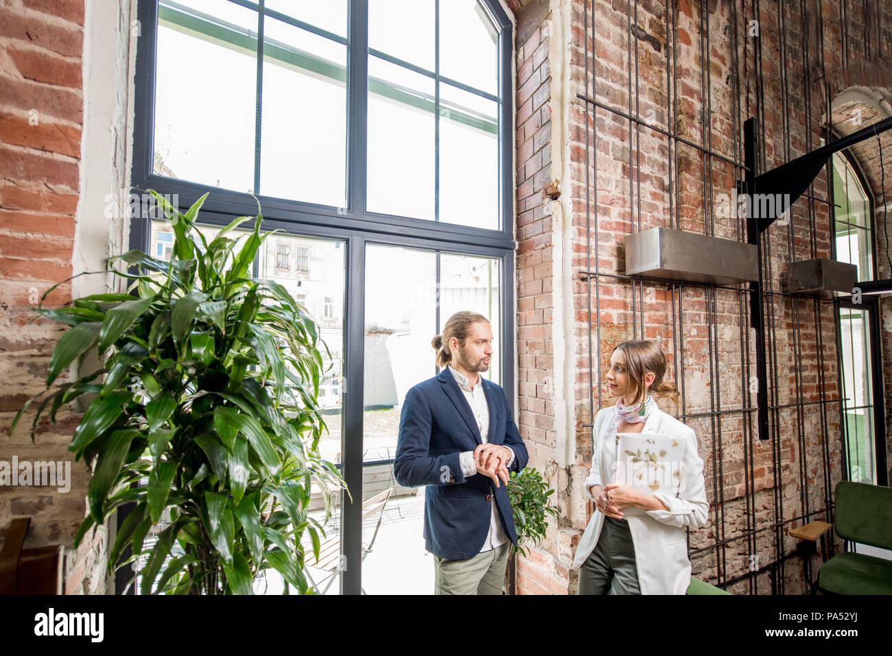 Business people having a conversation standing near the window in the ...