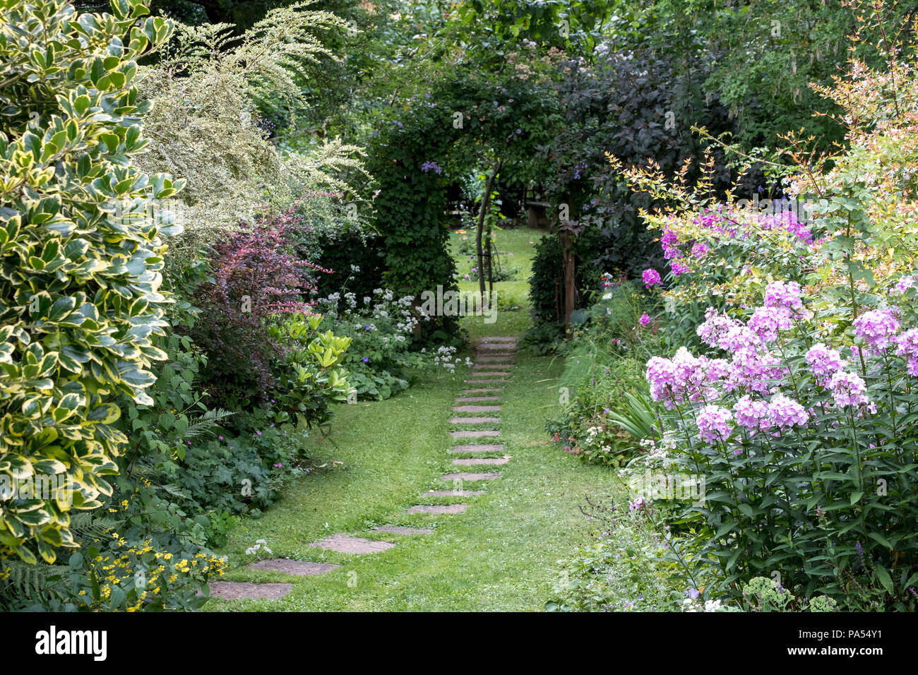 Well kept garden with lawn, stepping stones and well stocked flower ...