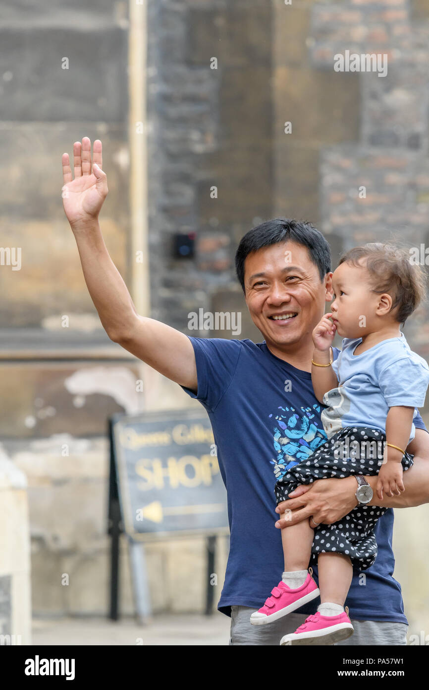 A happy, smiling, chinese man with child waves as he poses for a ...