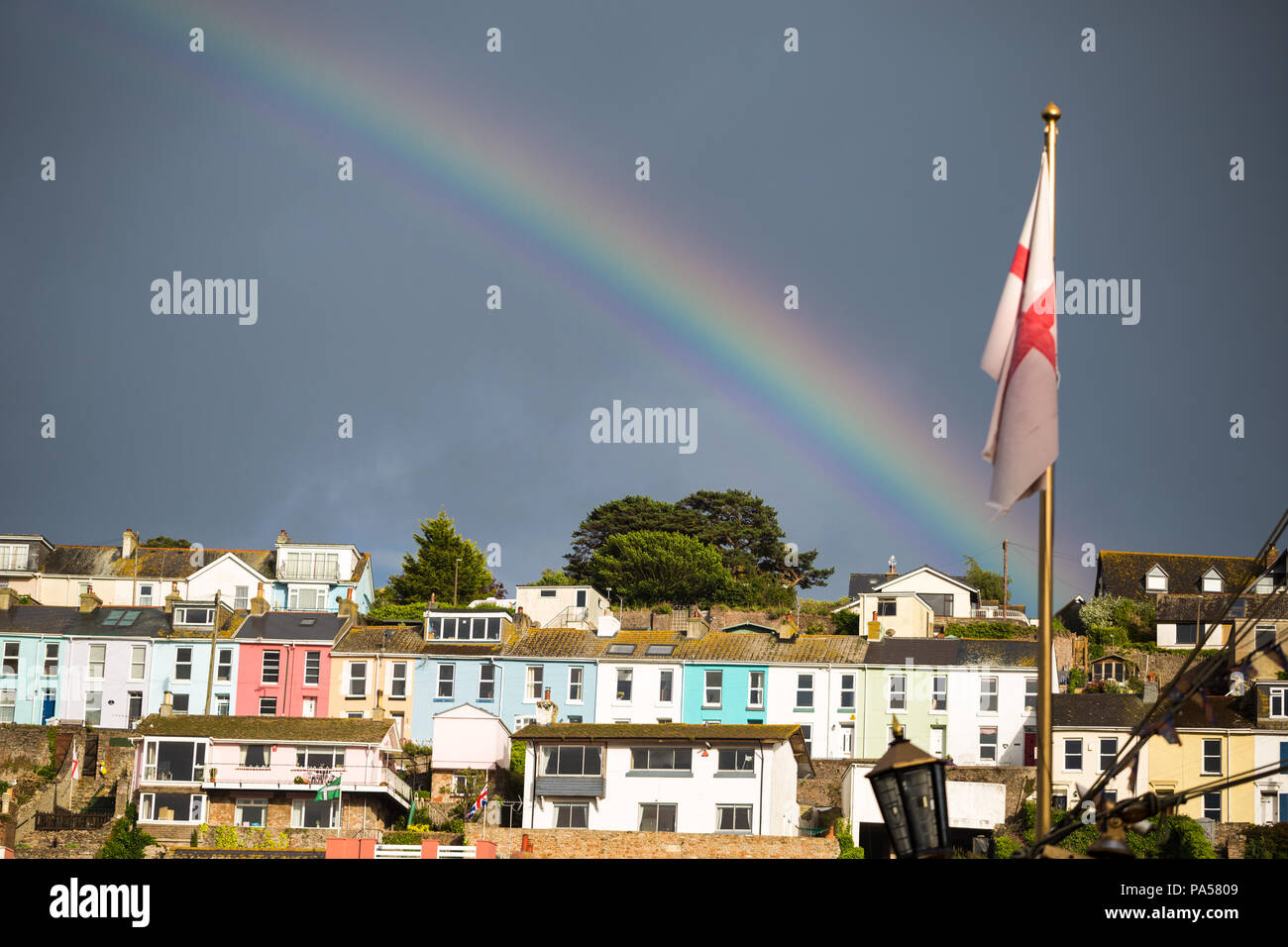 Colourful seaside homes with dark sky and rainbow, with St. Georges ...