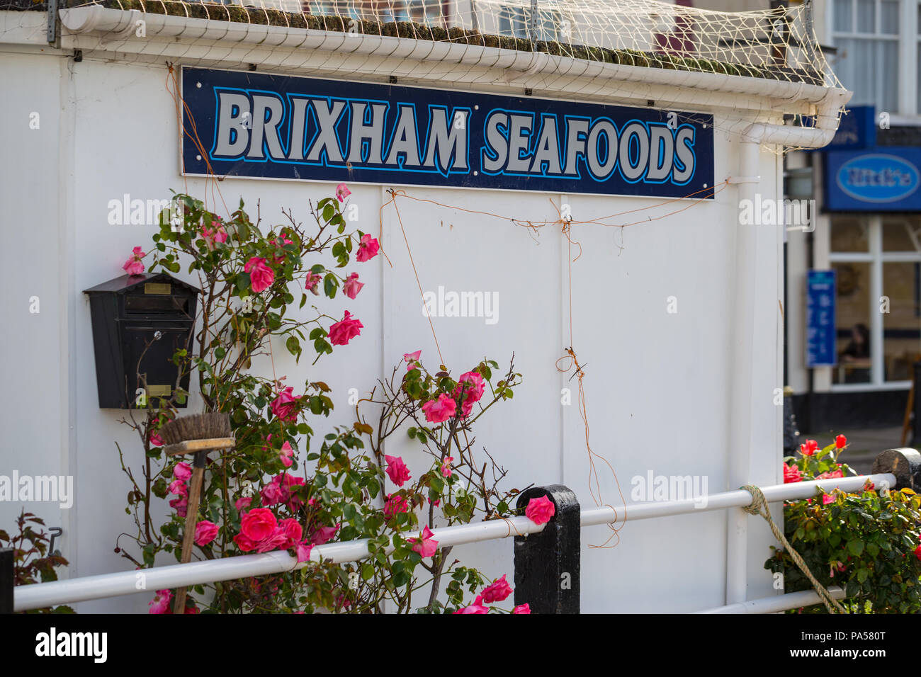 Brixham seafoods sign, at the harbour with pink roses, white wall ...
