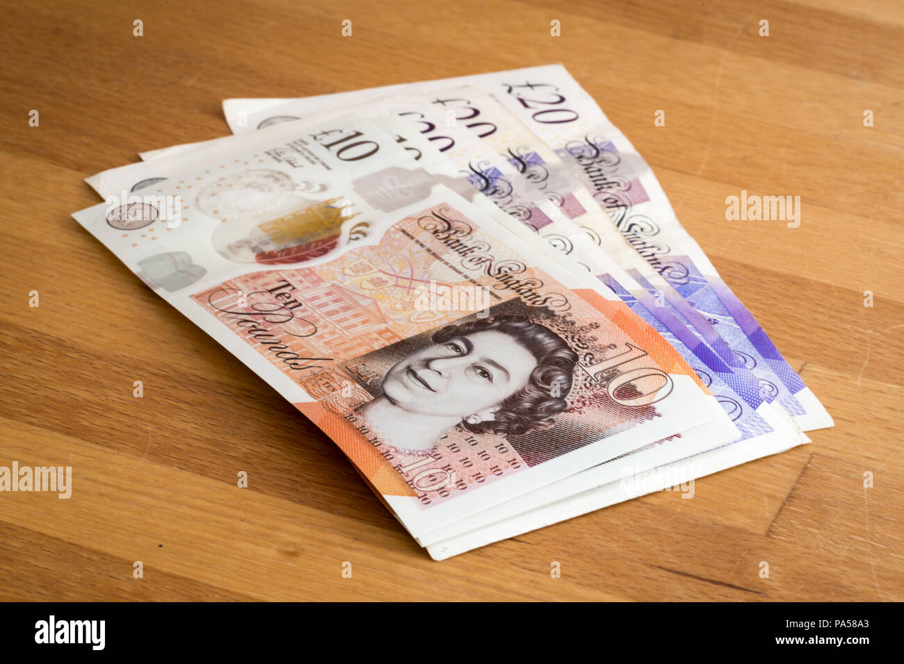 £10 and £20 pound notes on a wooden counter top Stock Photo - Alamy