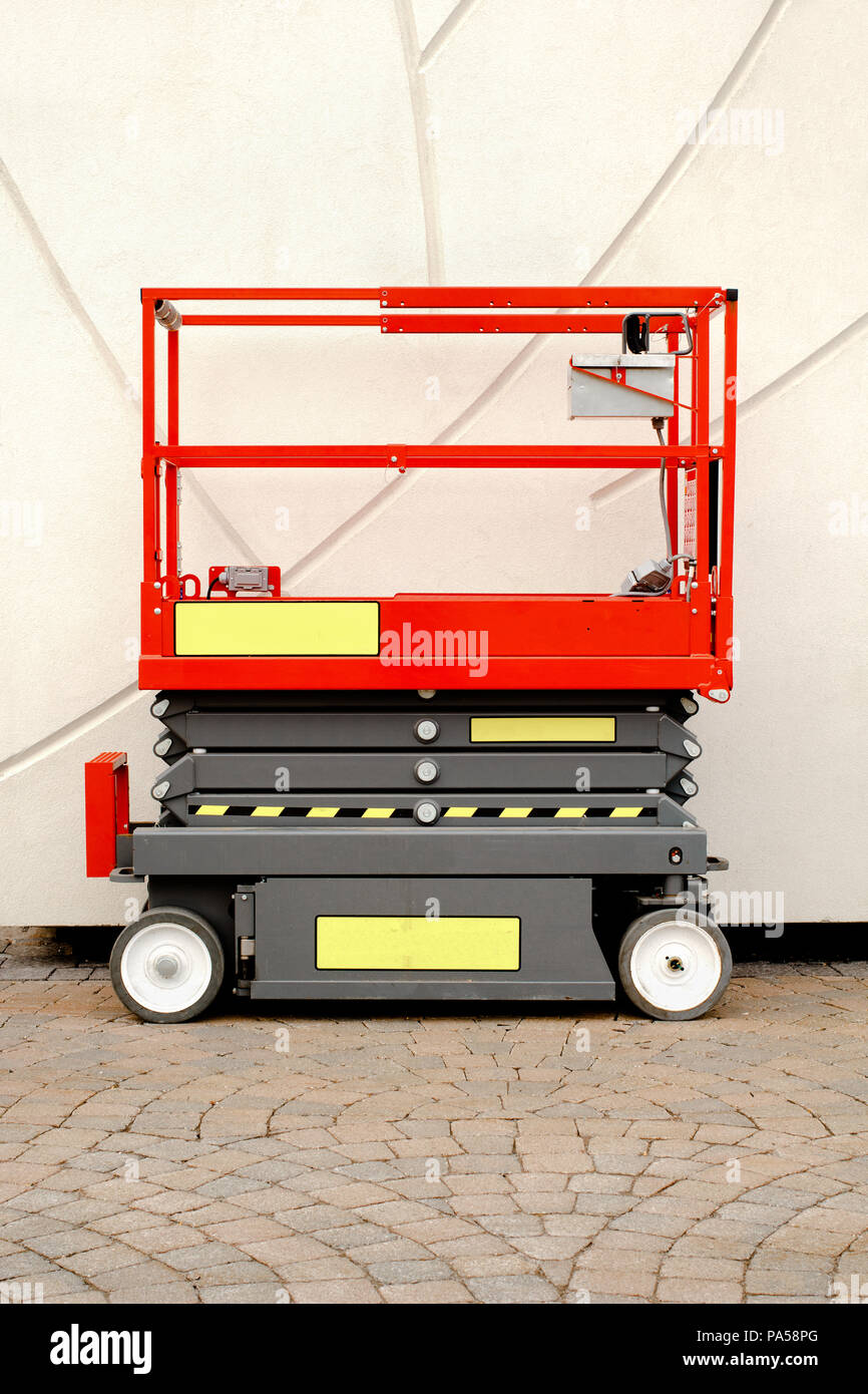 Hydraulic scissor work lift in front of modern facade Stock Photo - Alamy