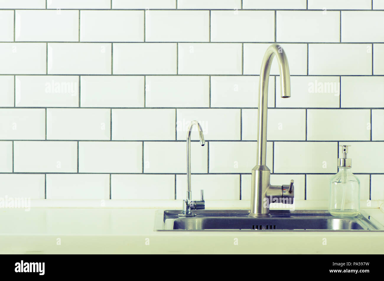 Water tap. White kitchen design. Mixer tap with flowing water on brick ...