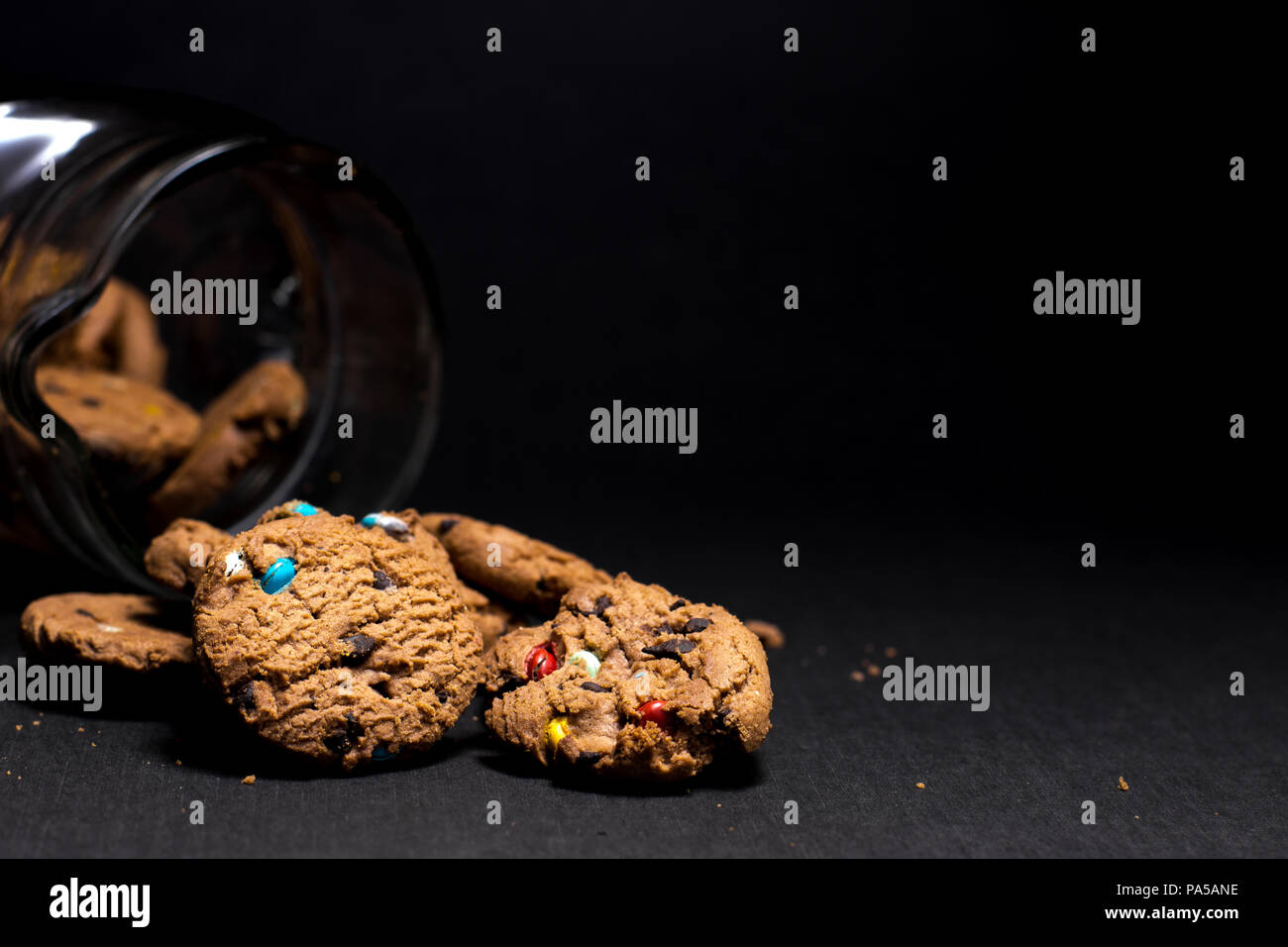 Cookie jar on black background with biscuits spilling out Stock Photo ...