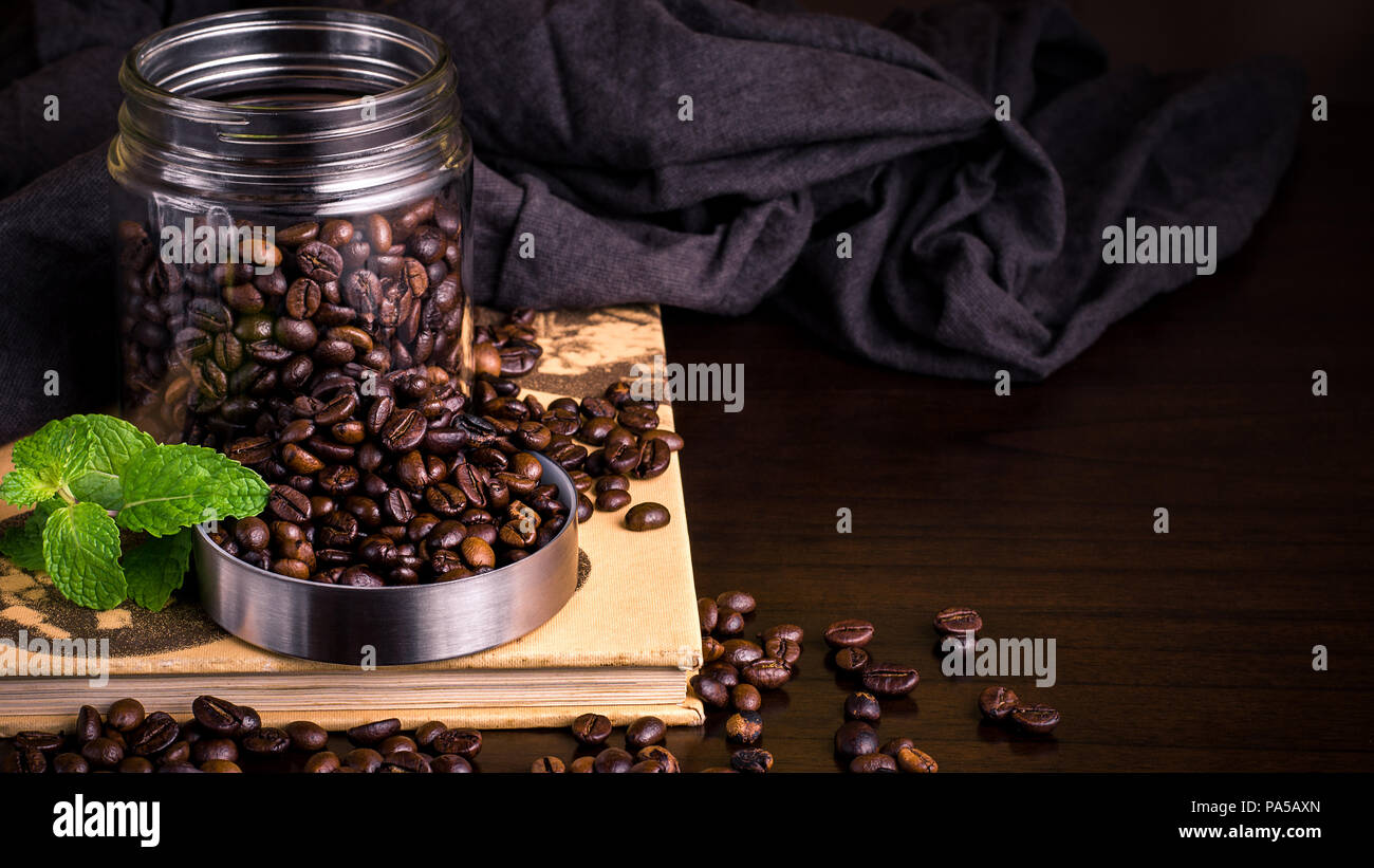 Dark coffee shop scene with coffee beans and fresh mint on wooden table ...