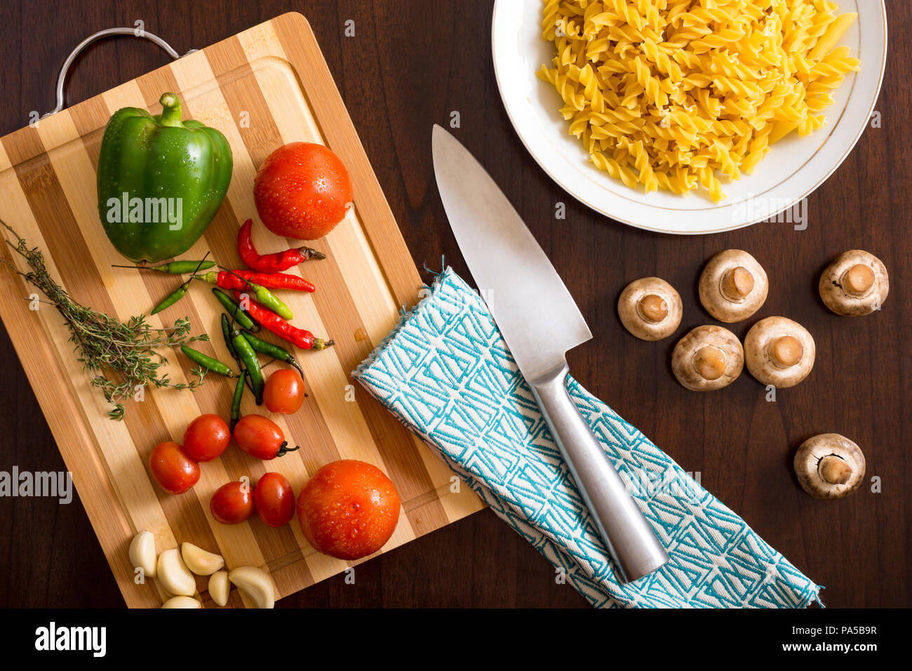 Flat lay table top image with pasta and ingredients on chopping board ...