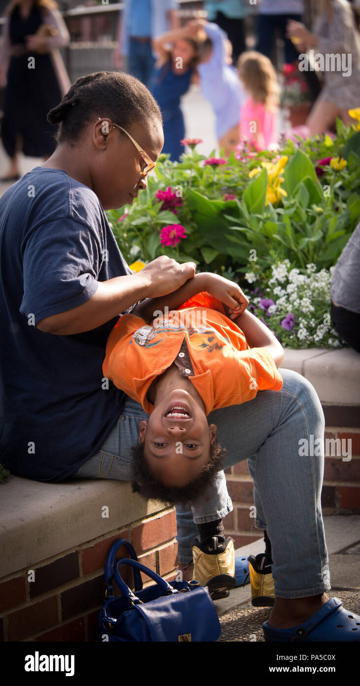 Vertical photo of boy laying on mothers lap with a big smile, laughing ...