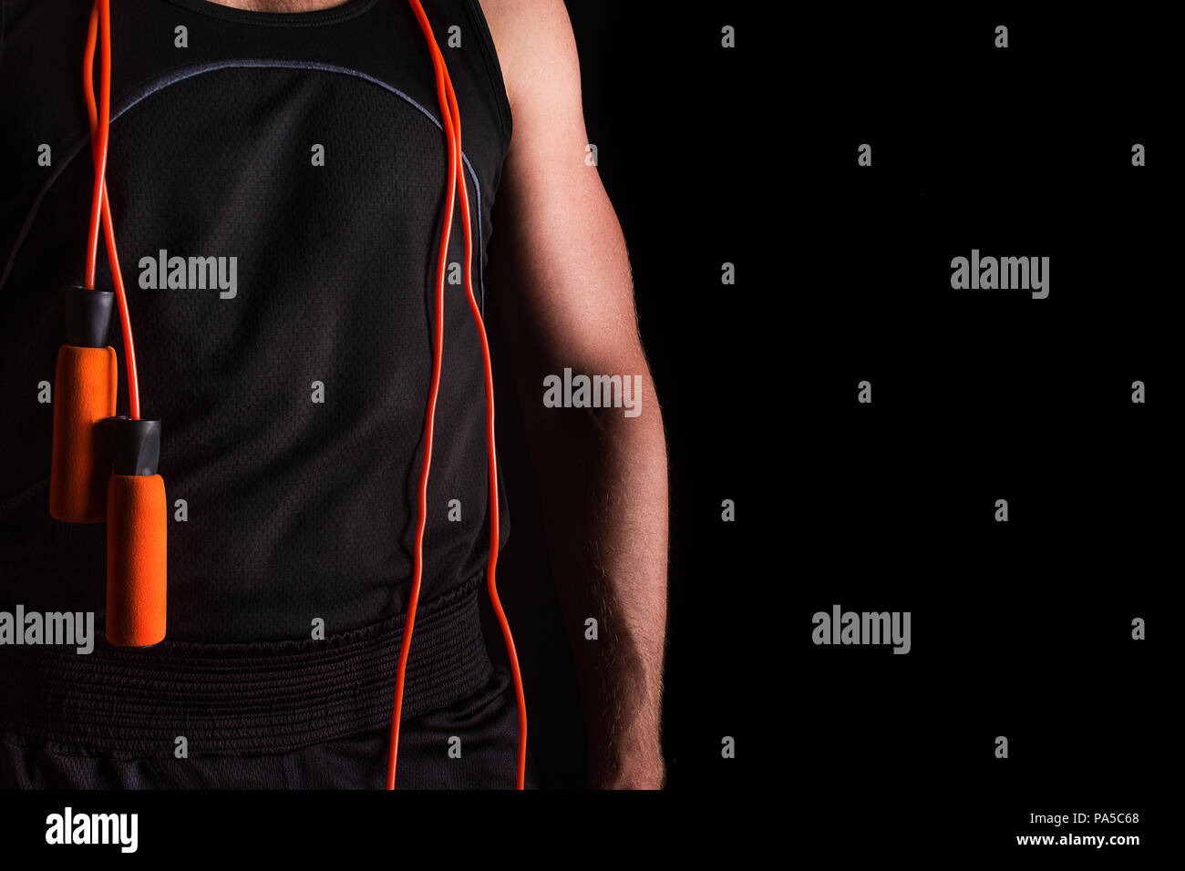 Adult caucasian male with skipping rope around his neck on black ...