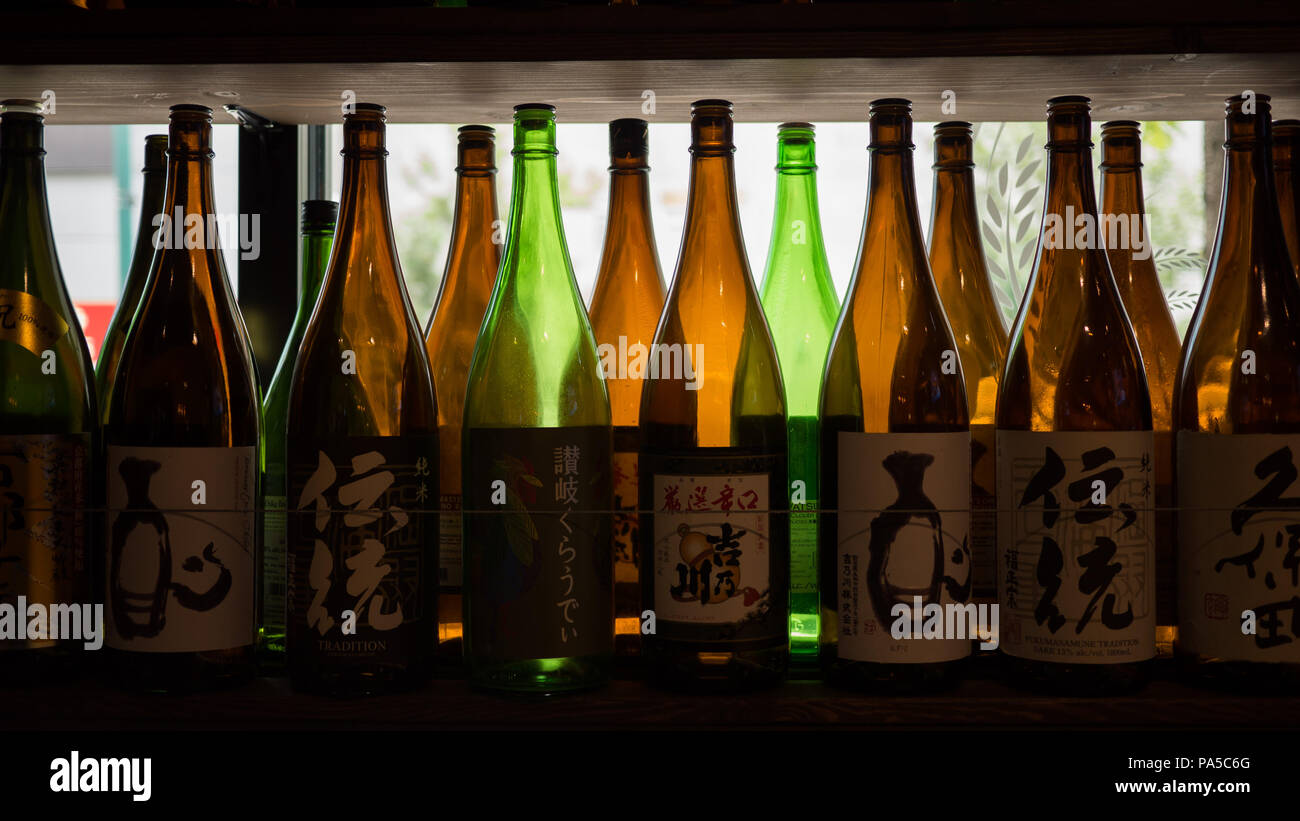 Large sake bottles backlit in restaurant window Stock Photo - Alamy