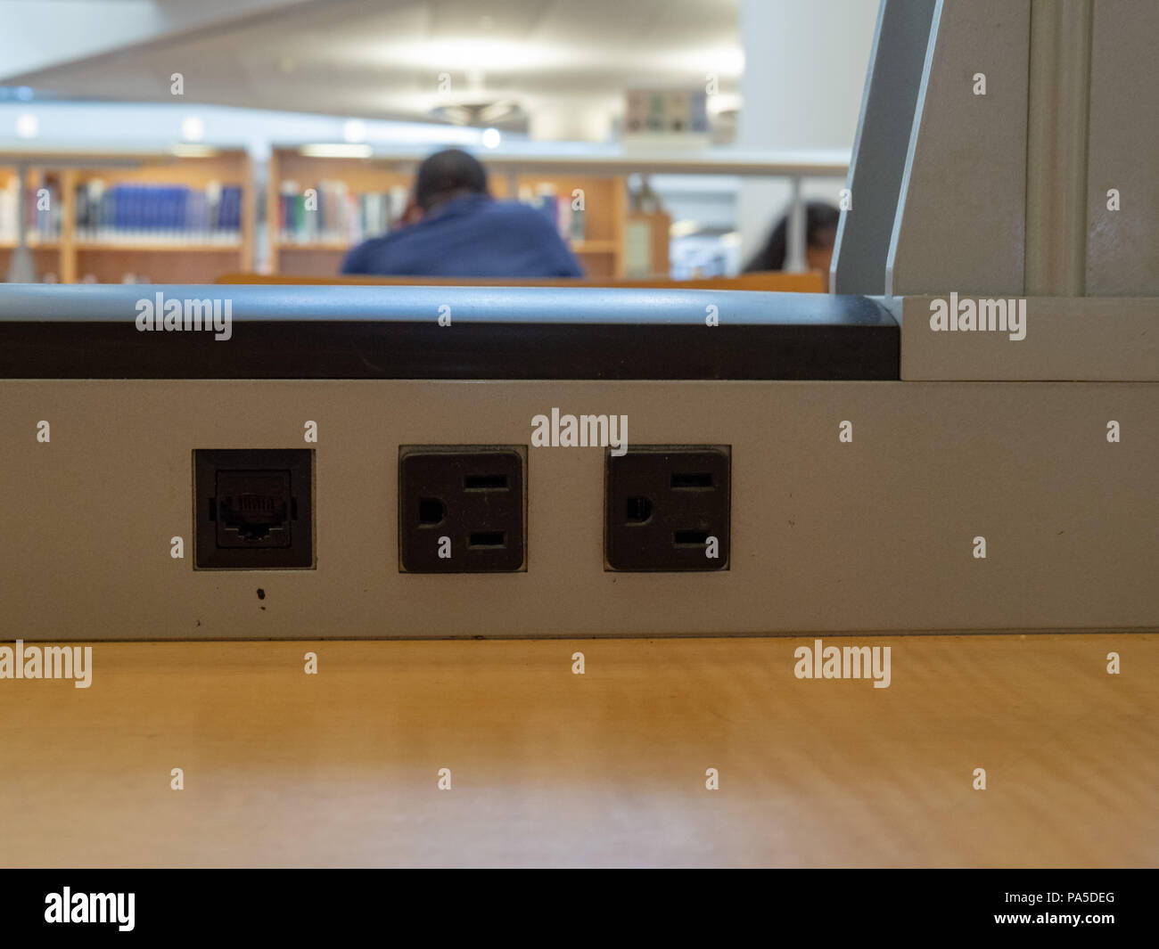 Row of electrical plug outlets in a library with man in background ...