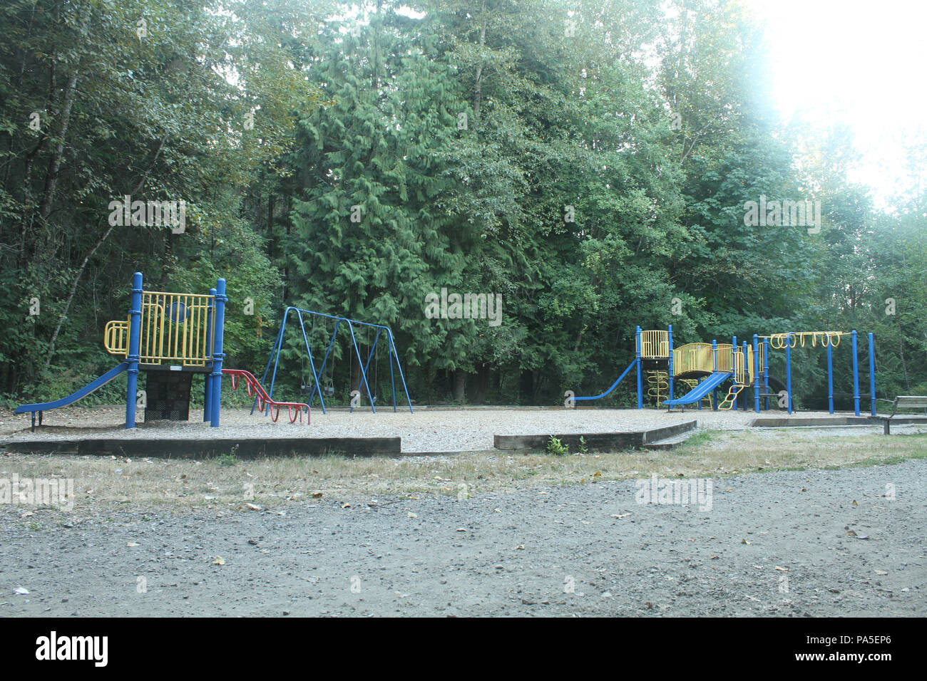 Blue and yellow playground equipment set on the edge of a forest Stock ...