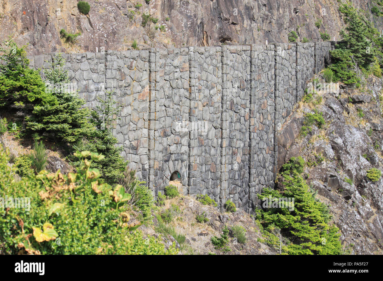 The view of a bridge along a cliff face made from boulders giving it a ...