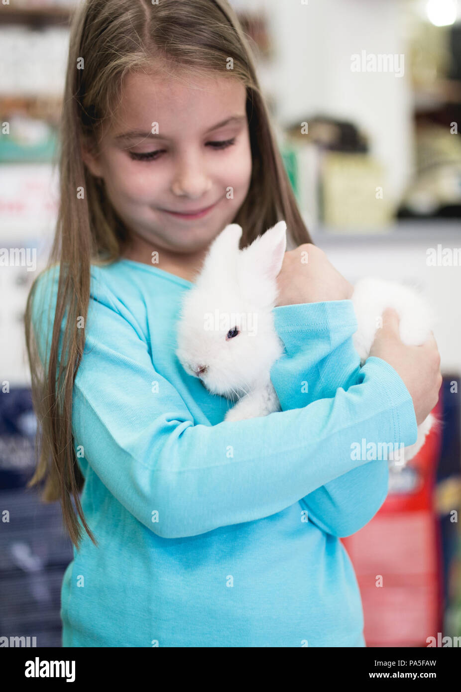 Cute little girl holding white bunny in pet shop Stock Photo - Alamy