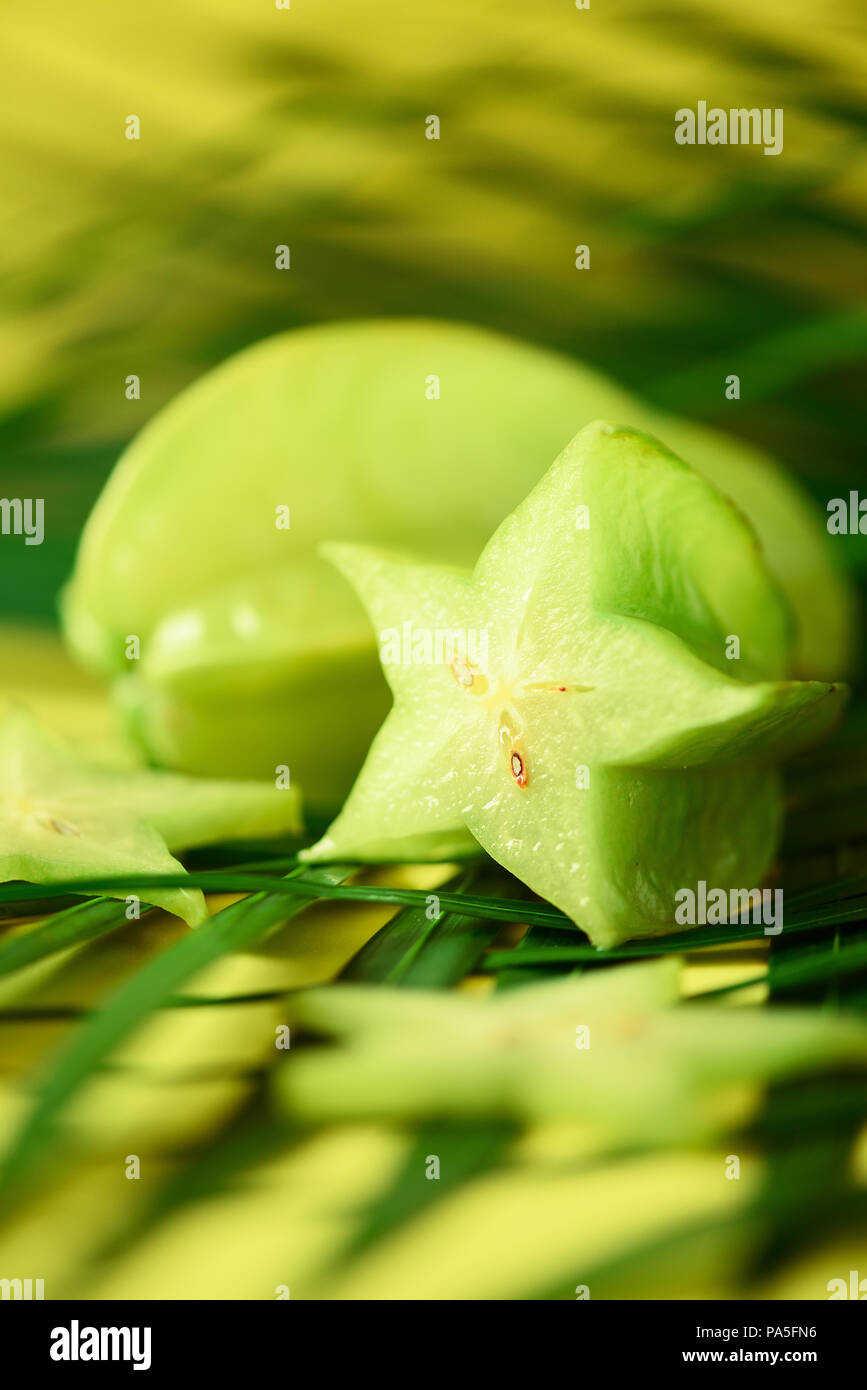 Exotic star fruit or averrhoa carambola over tropical green palm leaves ...