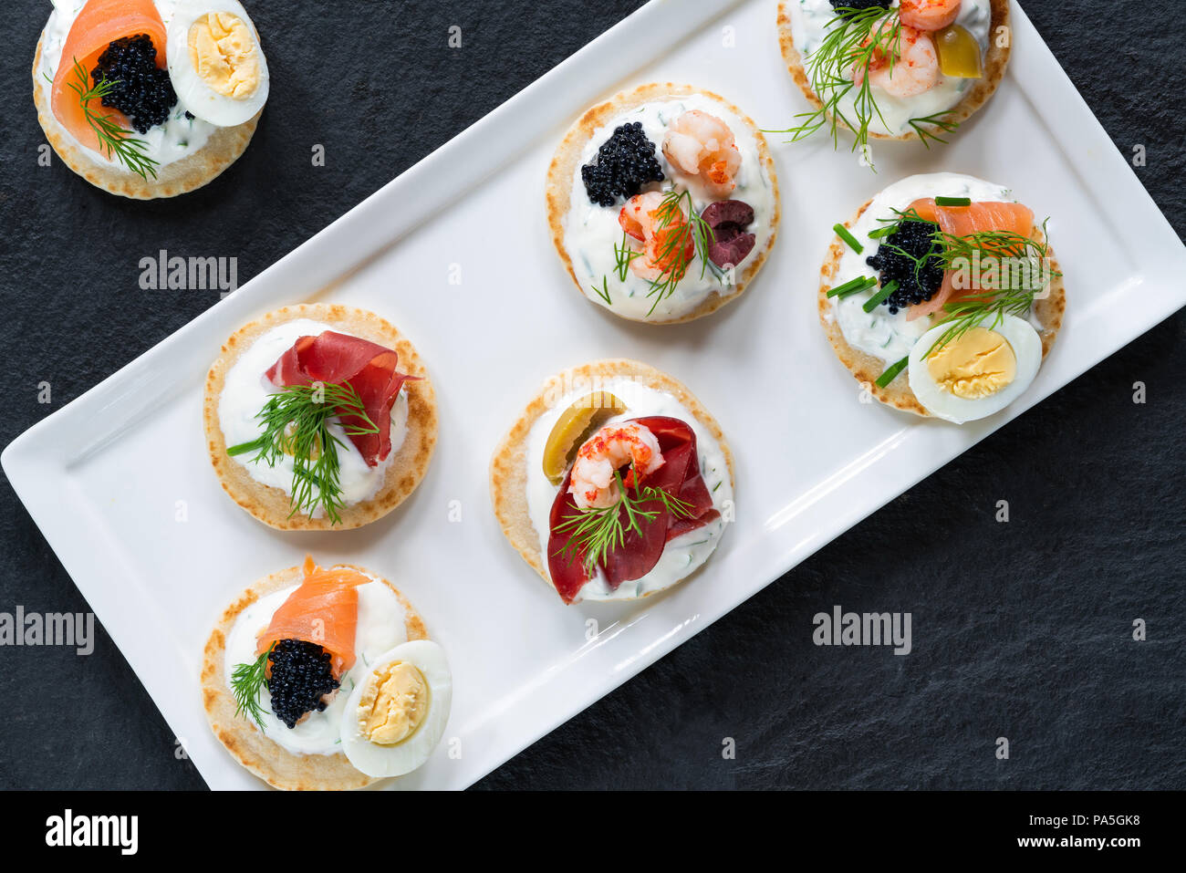 Selection of cocktail blinis with salmon, cured bresaola, crayfish ...