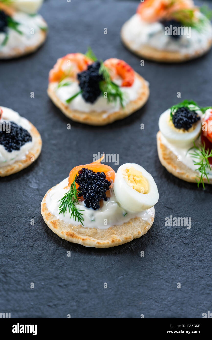 Selection of cocktail blinis with salmon, cured bresaola, crayfish ...
