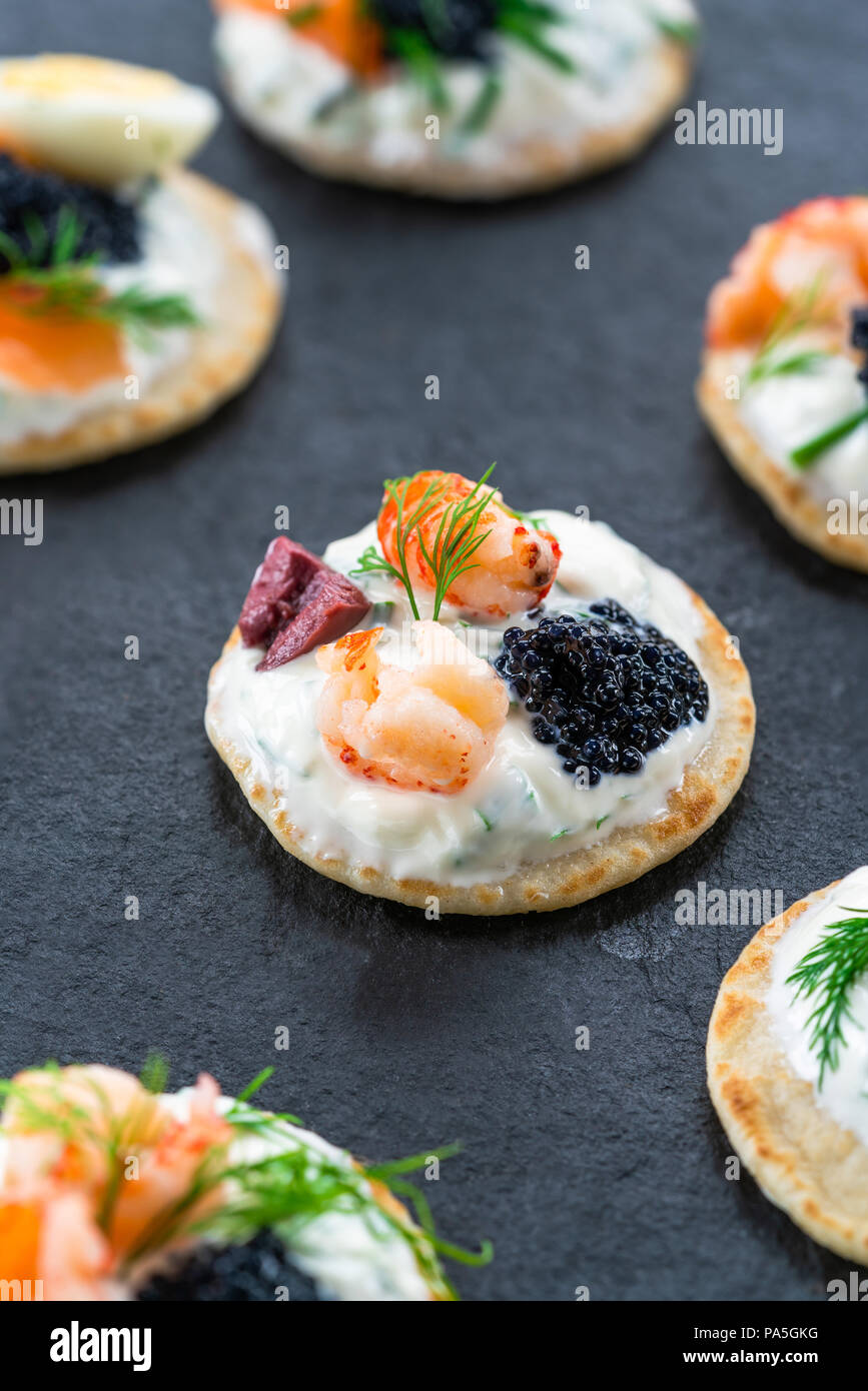 Selection of cocktail blinis with salmon, cured bresaola, crayfish ...