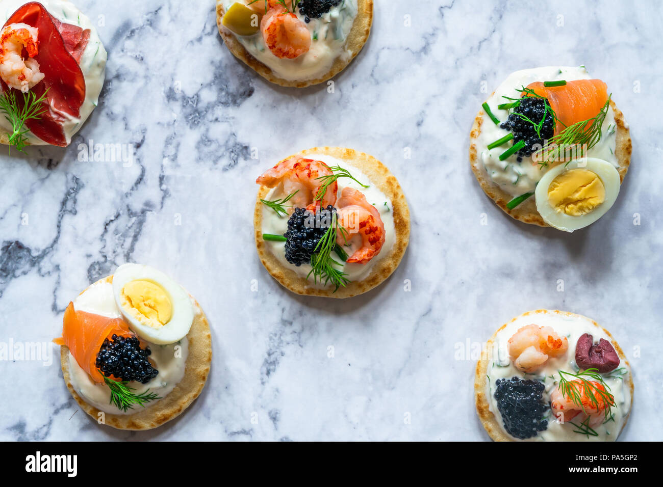 Selection of cocktail blinis with salmon, cured bresaola, crayfish ...