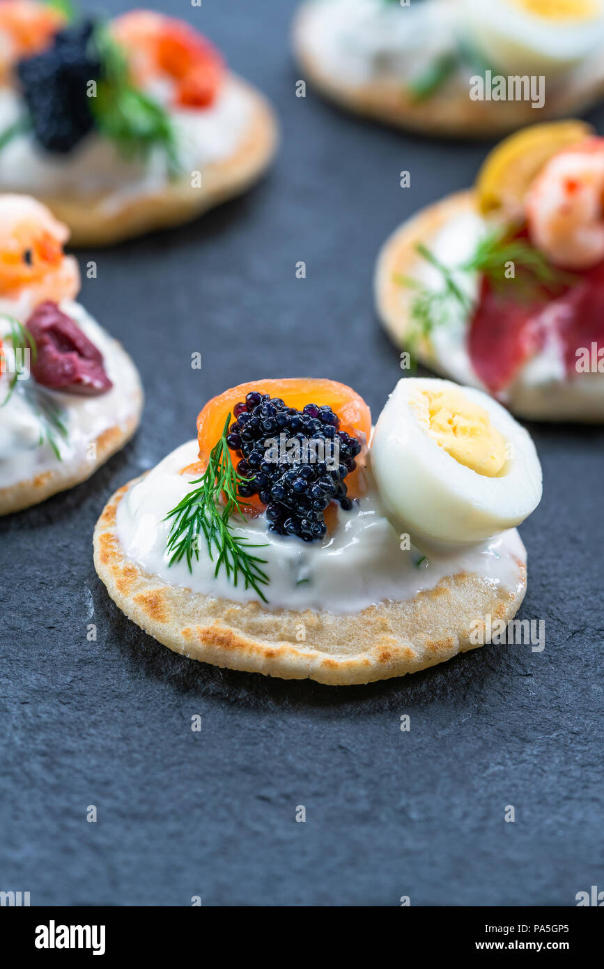 Selection of cocktail blinis with salmon, cured bresaola, crayfish ...