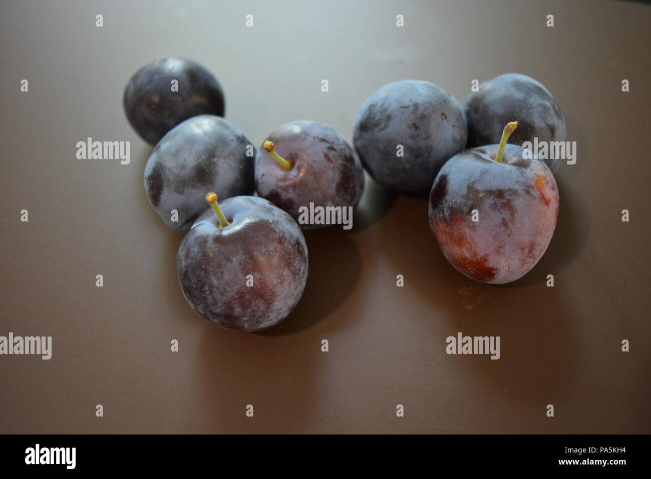 Fresh ripped plums on a brown matte background Stock Photo - Alamy