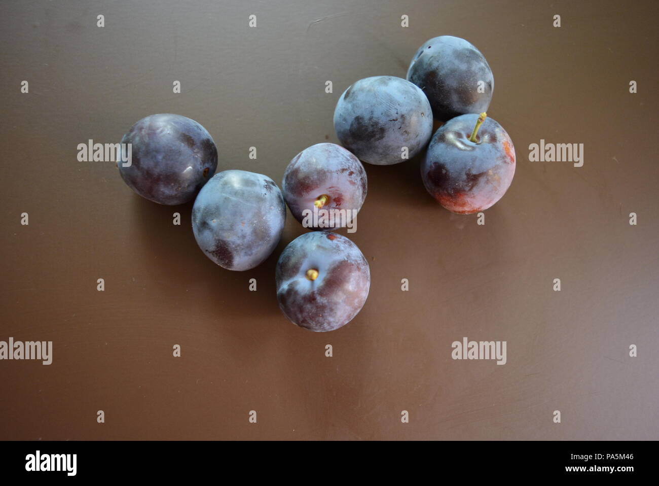 Fresh ripped plums on a brown matte background Stock Photo - Alamy