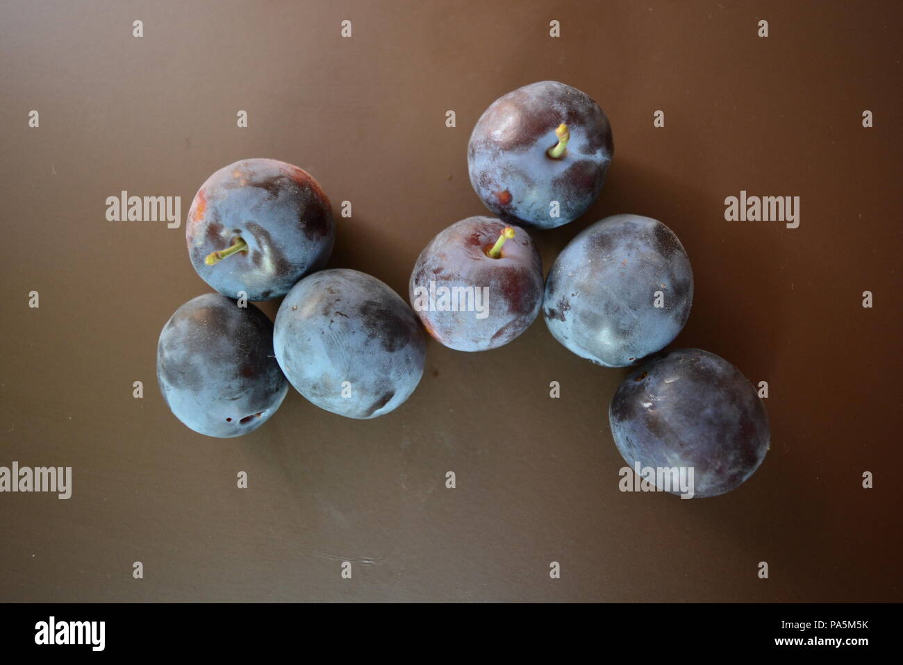 Fresh ripped plums on a brown matte background Stock Photo - Alamy