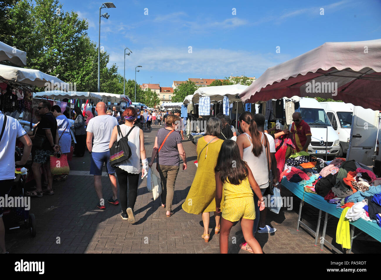 People looking around a bustling clothes market in Beziers, France ...