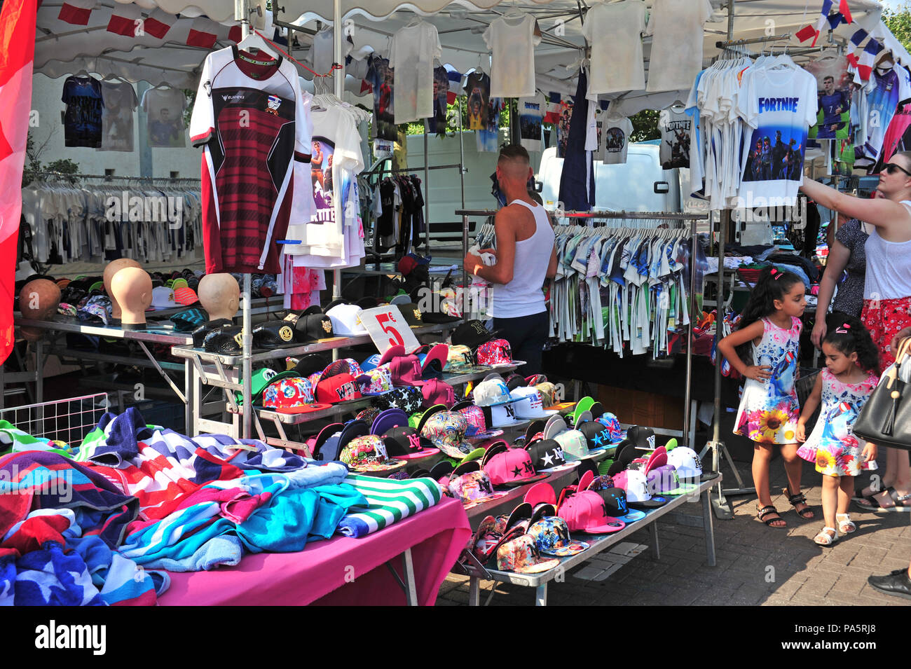 People looking around a bustling clothes market in Beziers, France ...