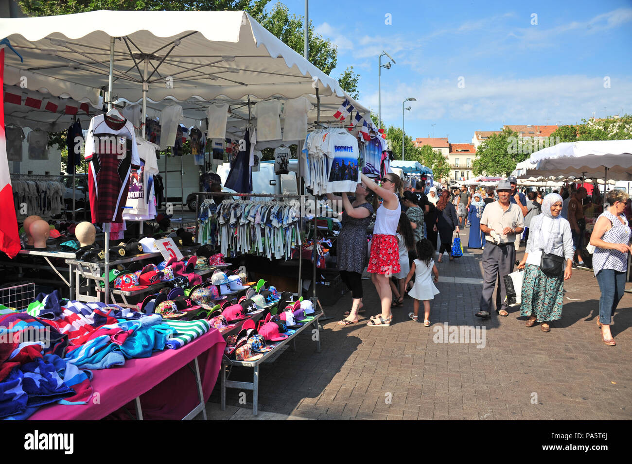 People looking around a bustling clothes market in Beziers, France ...