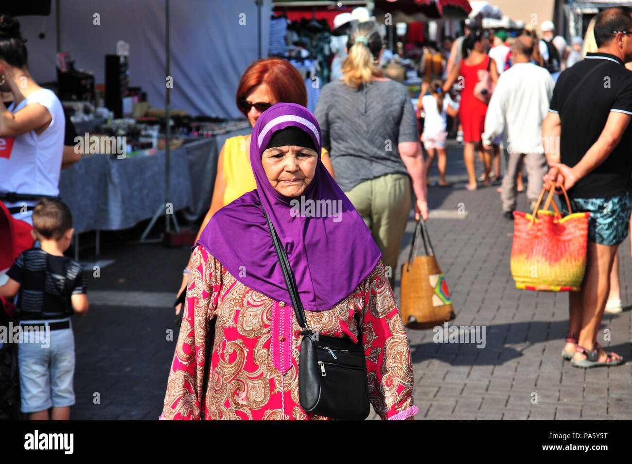 People looking around a bustling clothes market in Beziers, France ...