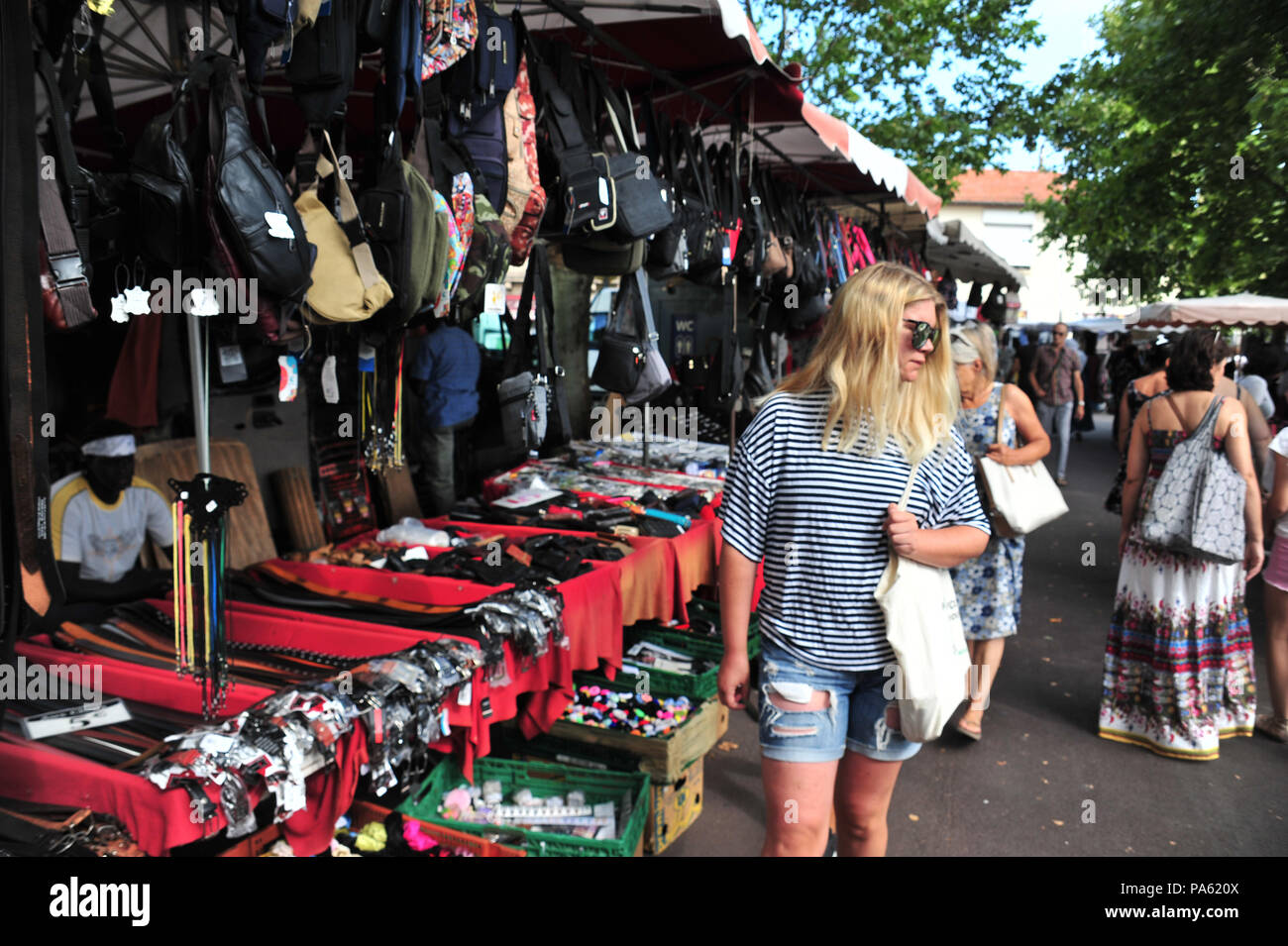 People looking around a bustling clothes market in Beziers, France ...