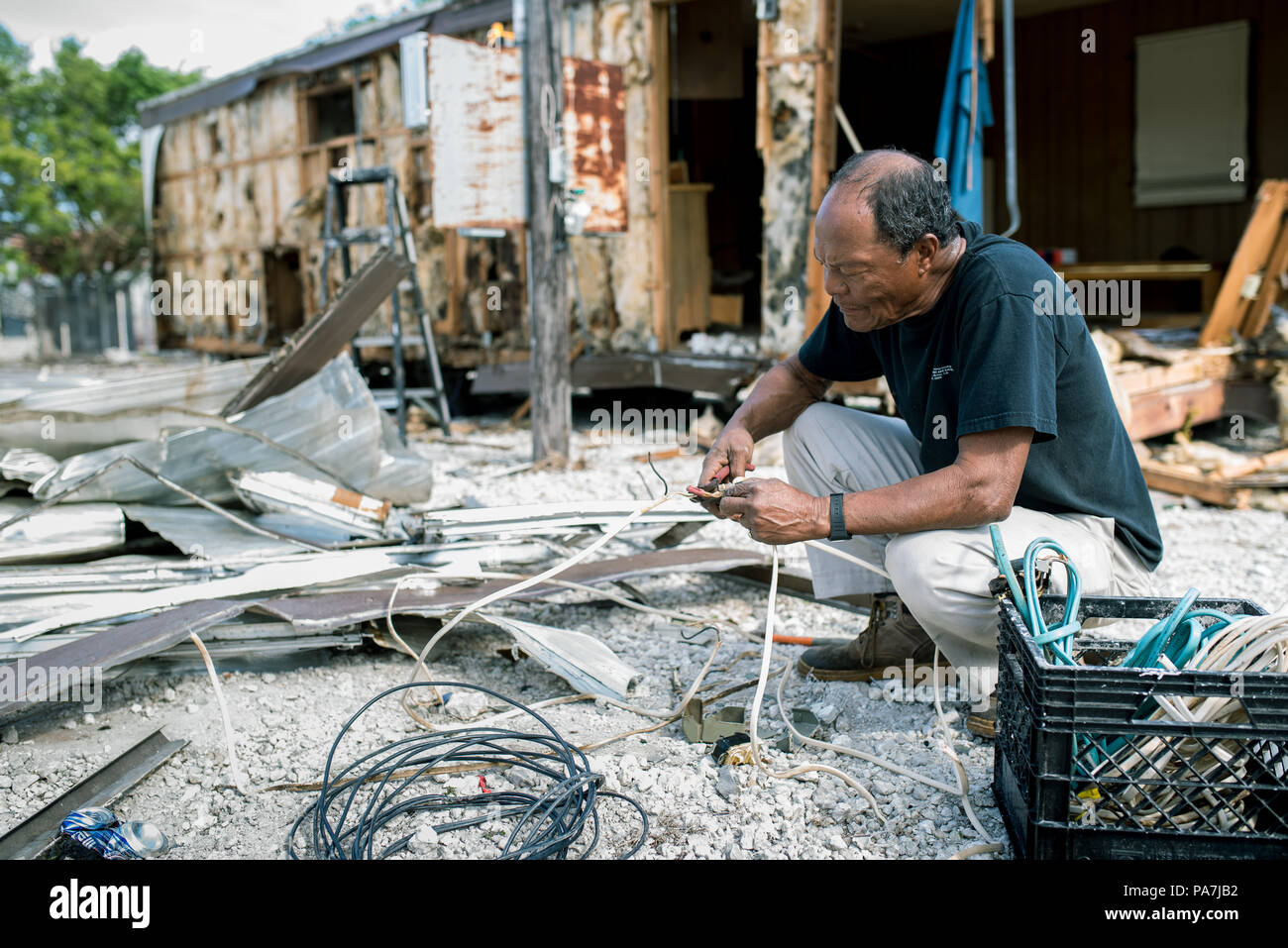 A man collecting scrap wires to sell and reuse in an abandoned trailer ...
