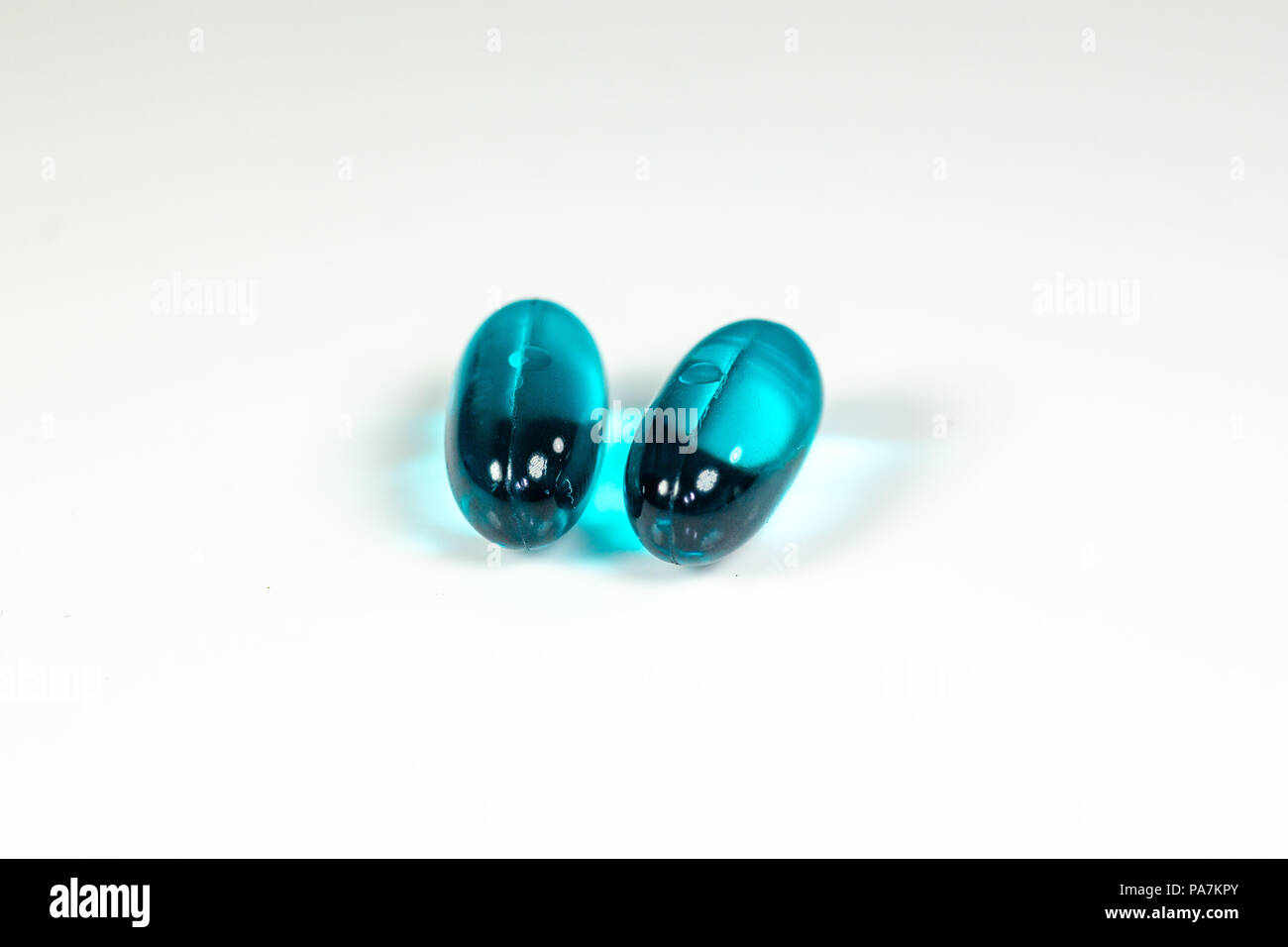 Two clear blue pills against the while surface of a pharmacy table ...
