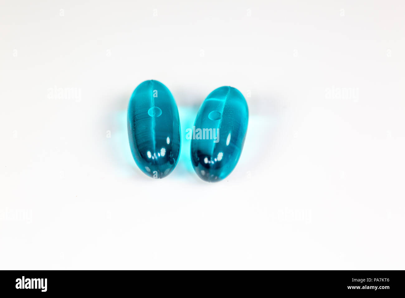 Two clear blue pills against the while surface of a pharmacy table ...