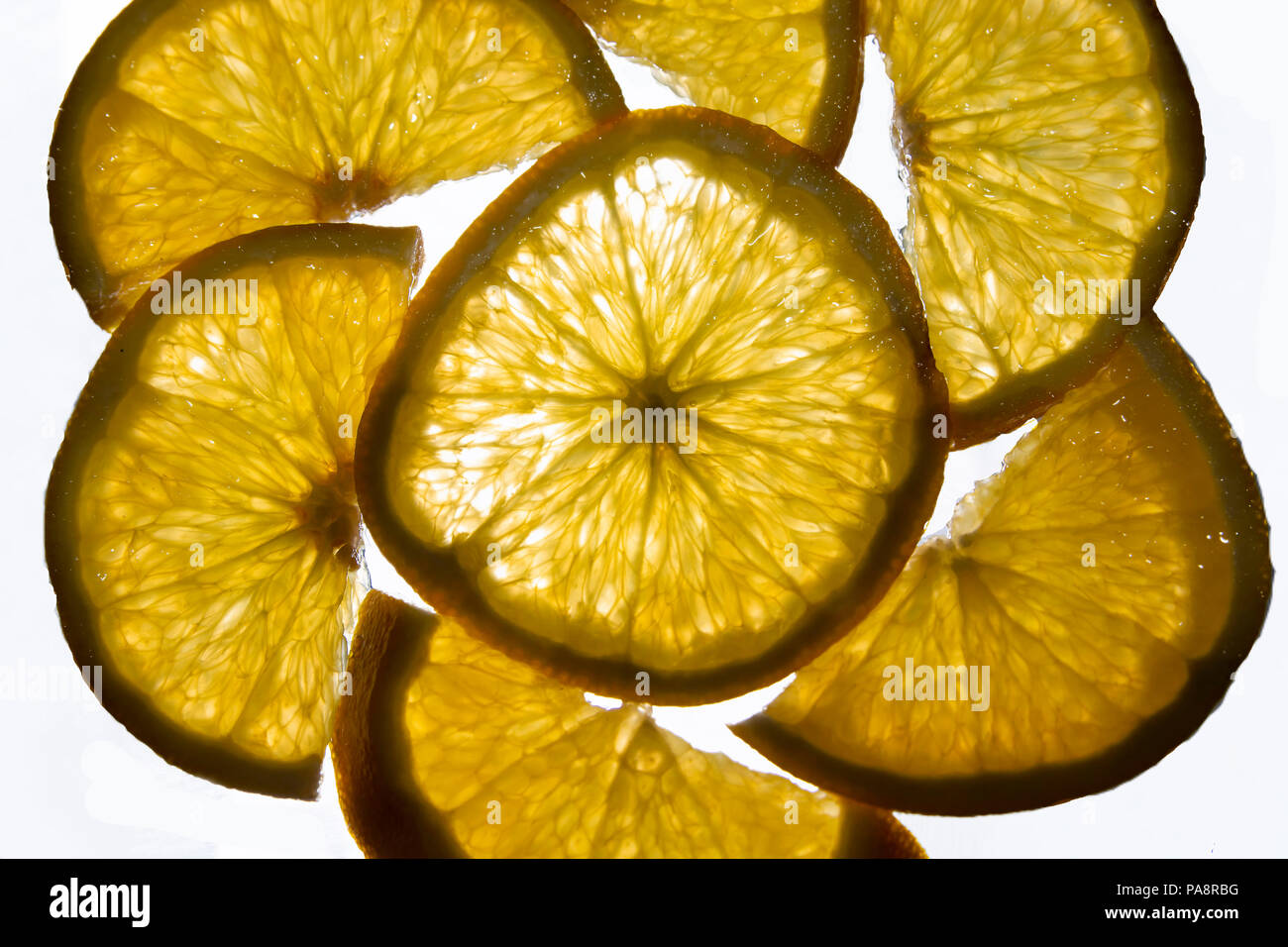 Slices of juicy citric fruit with back light and a white background ...