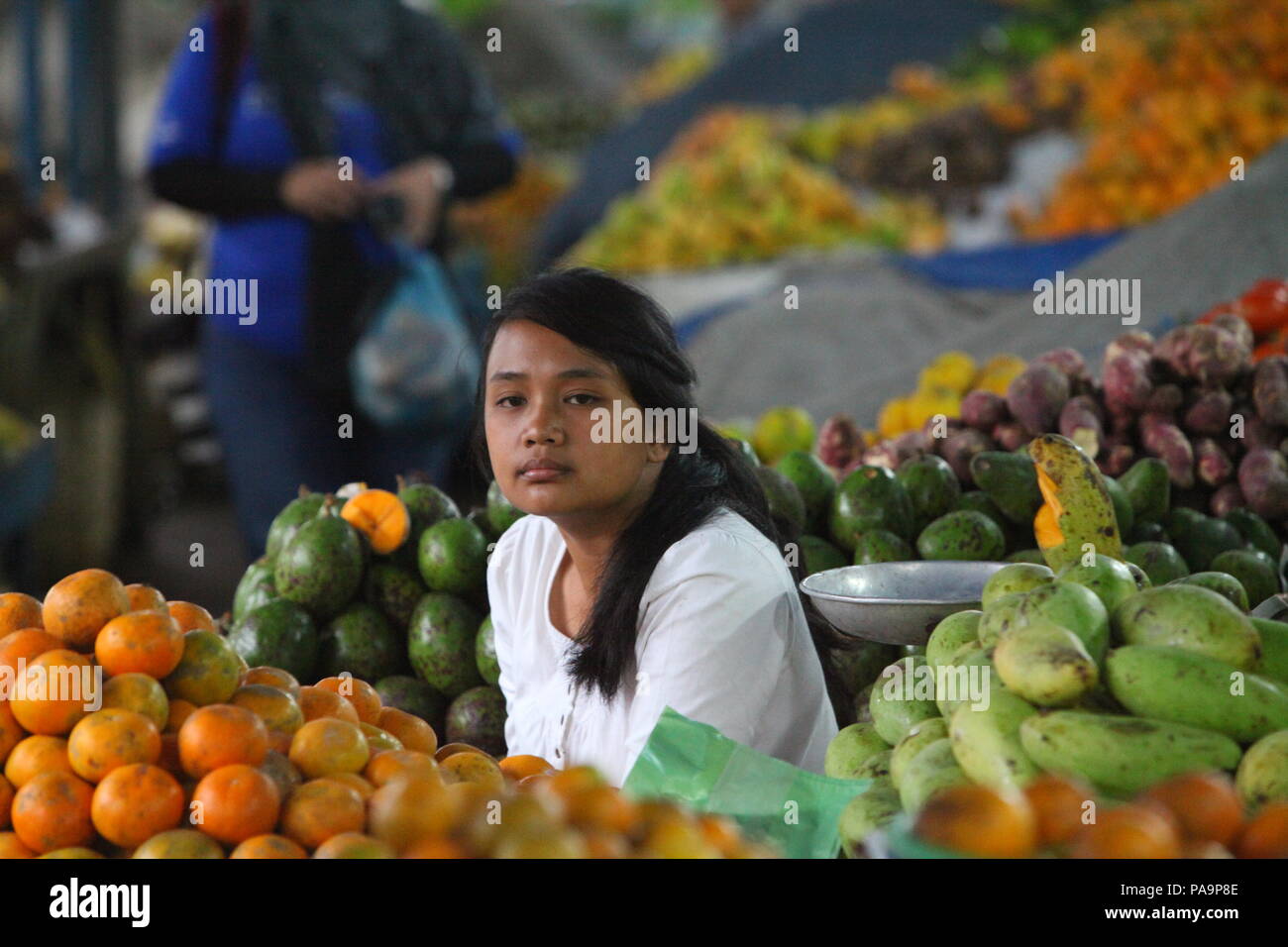 a girl selling vegetables and fruits at a village market in indonesia ...