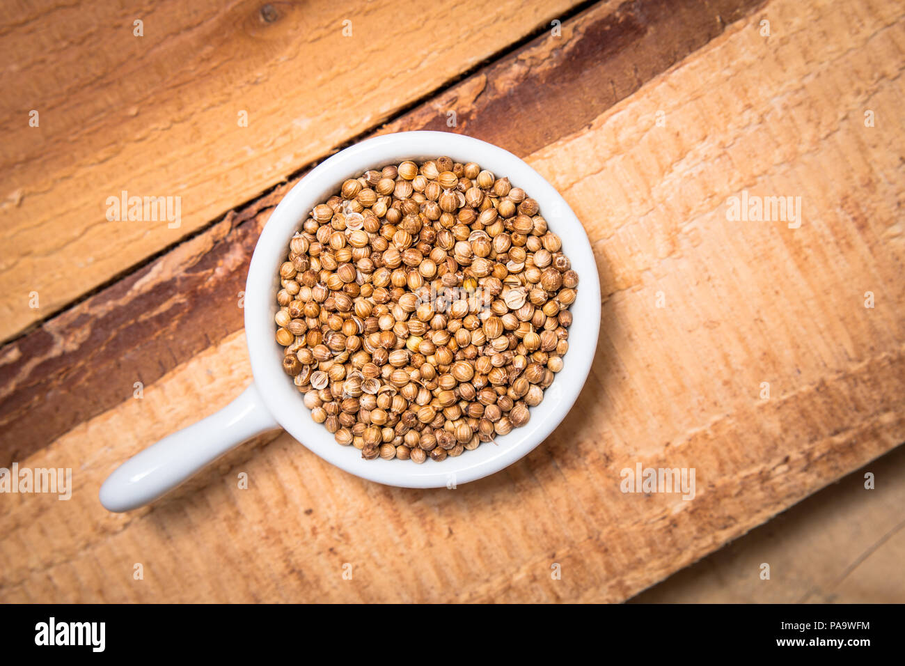 Exotic spices concept organic coriander seeds in white cup on wood ...