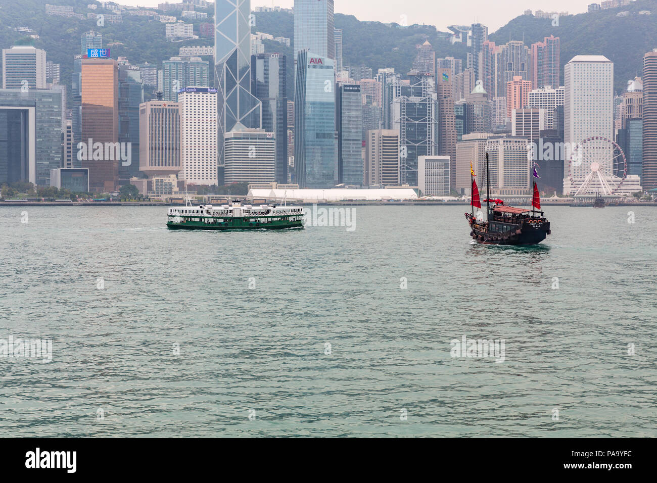 A Star Ferry boat crosses in front of a restaurant junk in Hong Kong ...