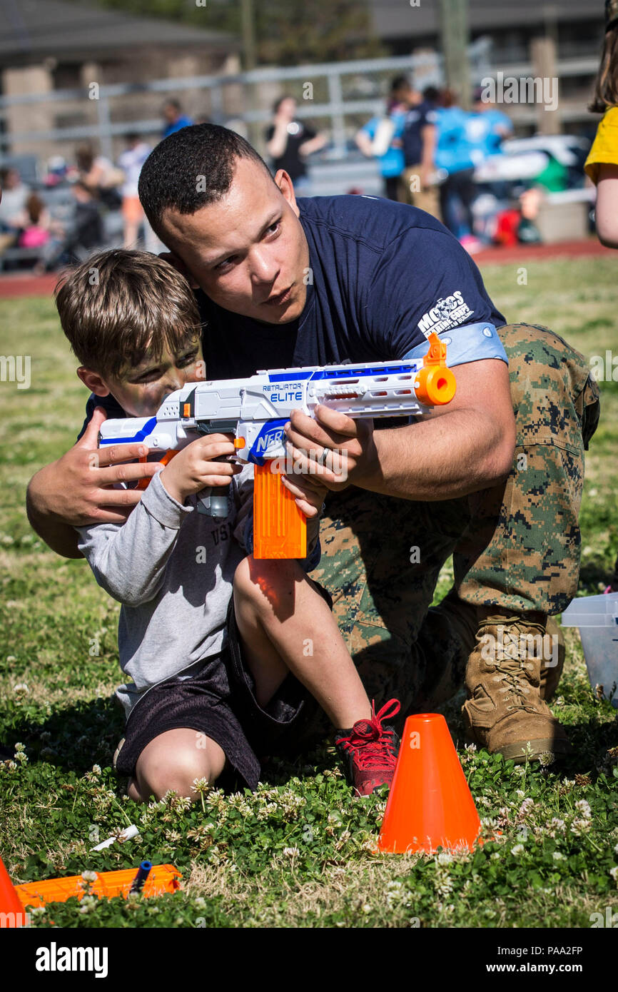 A Marine shows a child the fundamentals of marksmanship with a toy gun ...