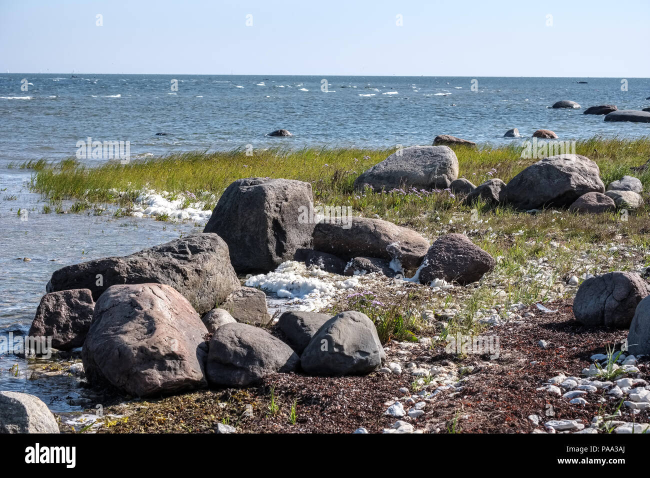 rocky sea beach with wide angle perspective over the sea with sunny sky ...