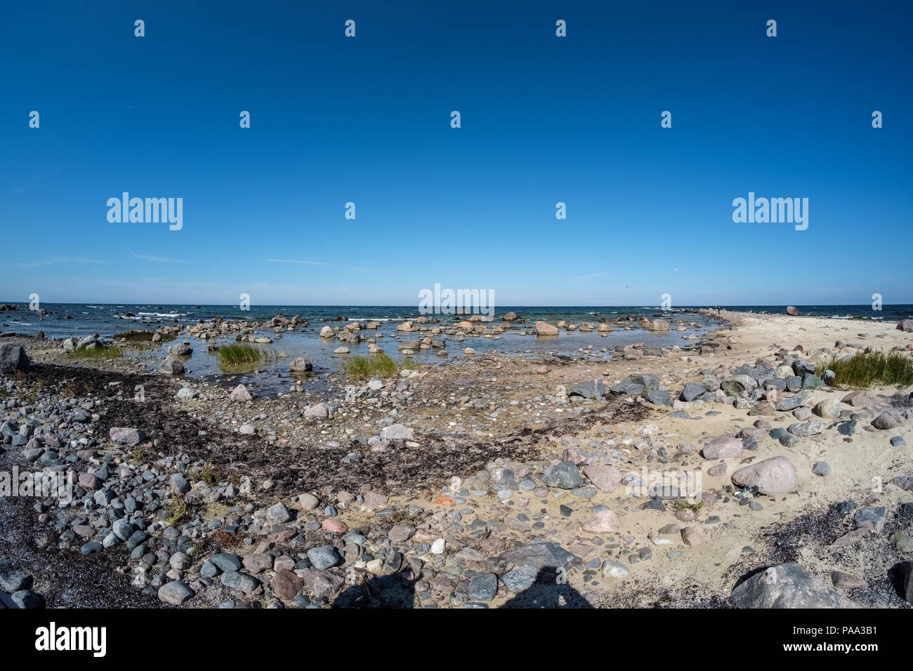 rocky sea beach with wide angle perspective over the sea with sunny sky ...