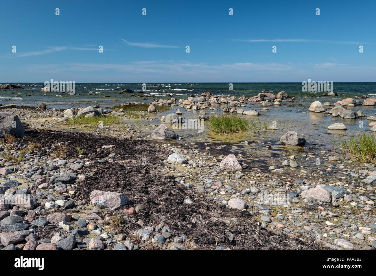 rocky sea beach with wide angle perspective over the sea with sunny sky ...