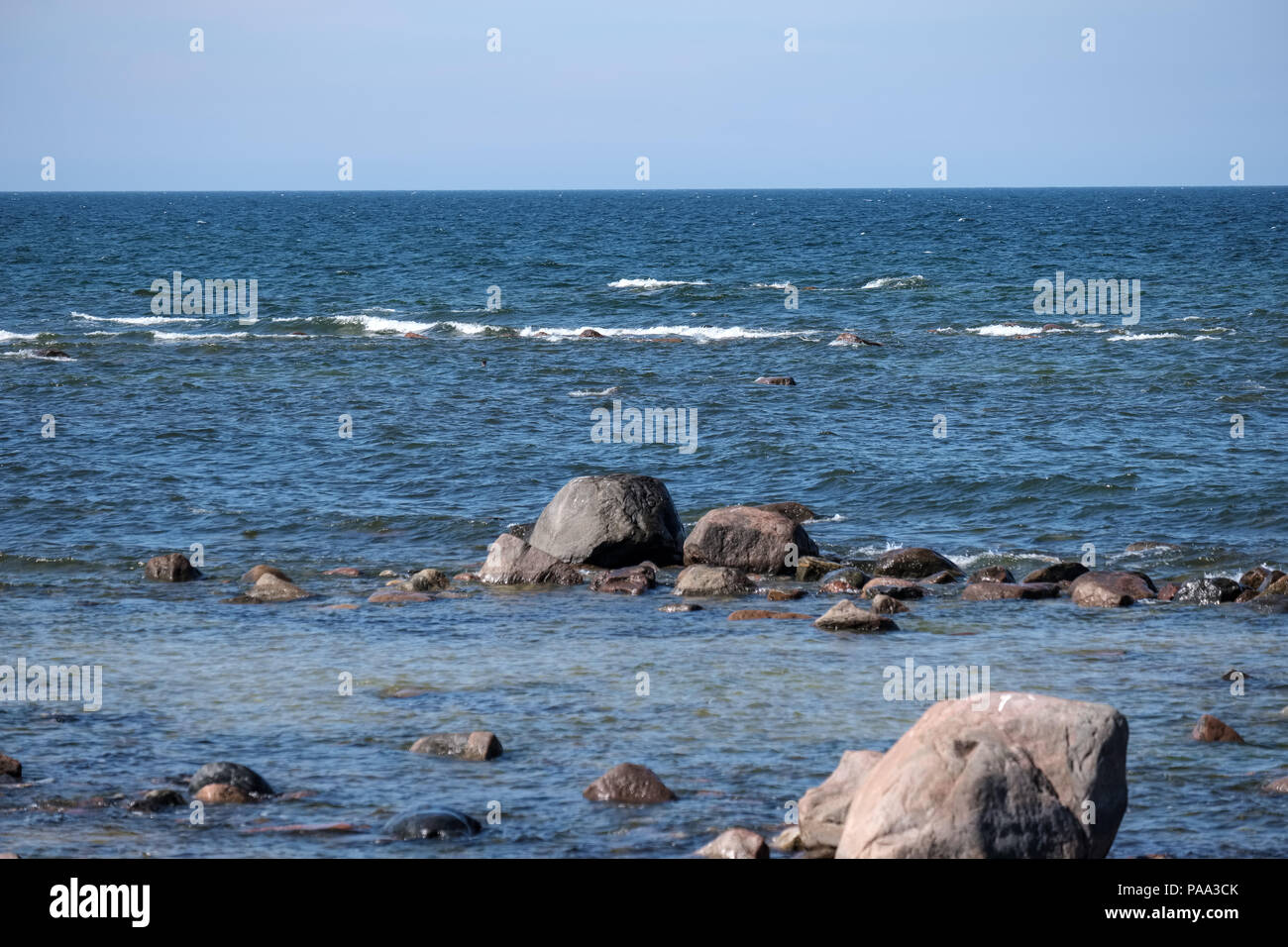 rocky sea beach with wide angle perspective over the sea with sunny sky ...