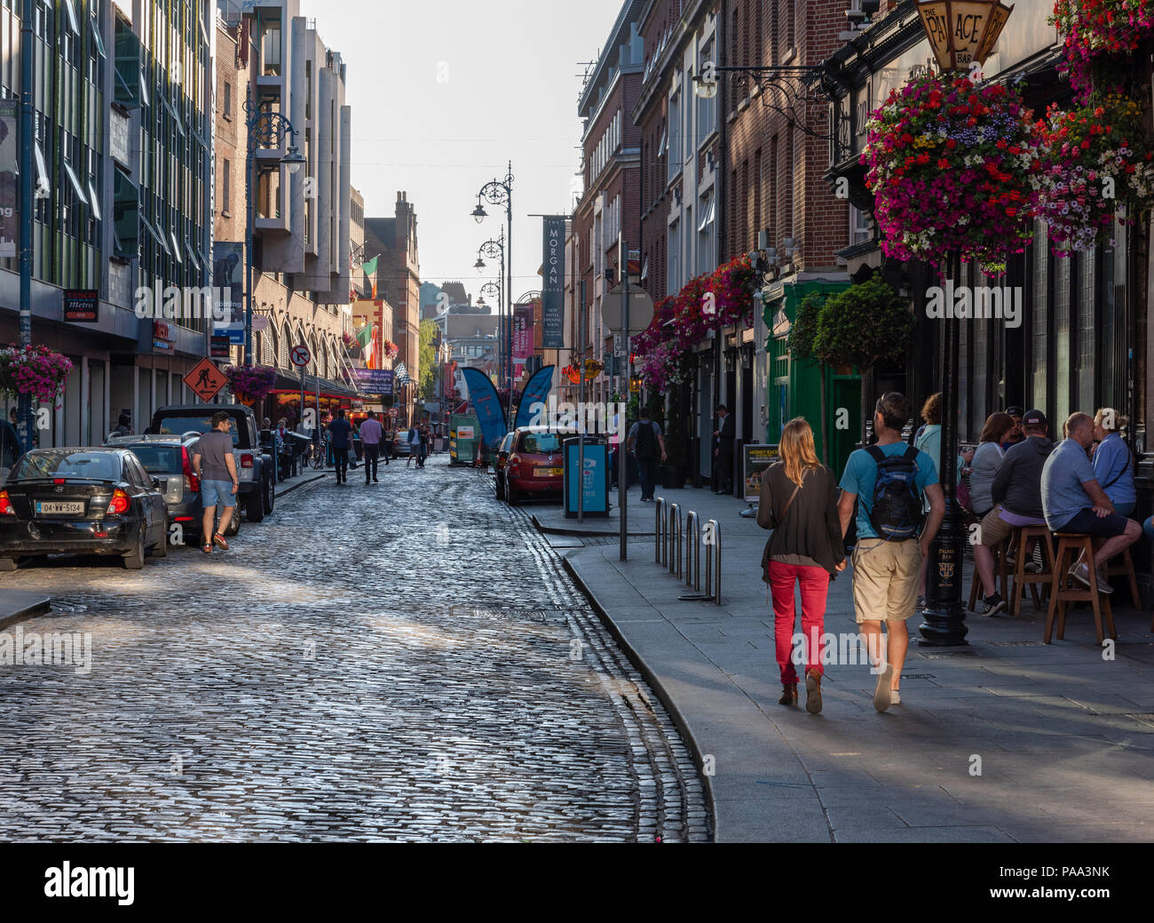 A couple holding hands walks down a street in Dublin as the nightlife ...