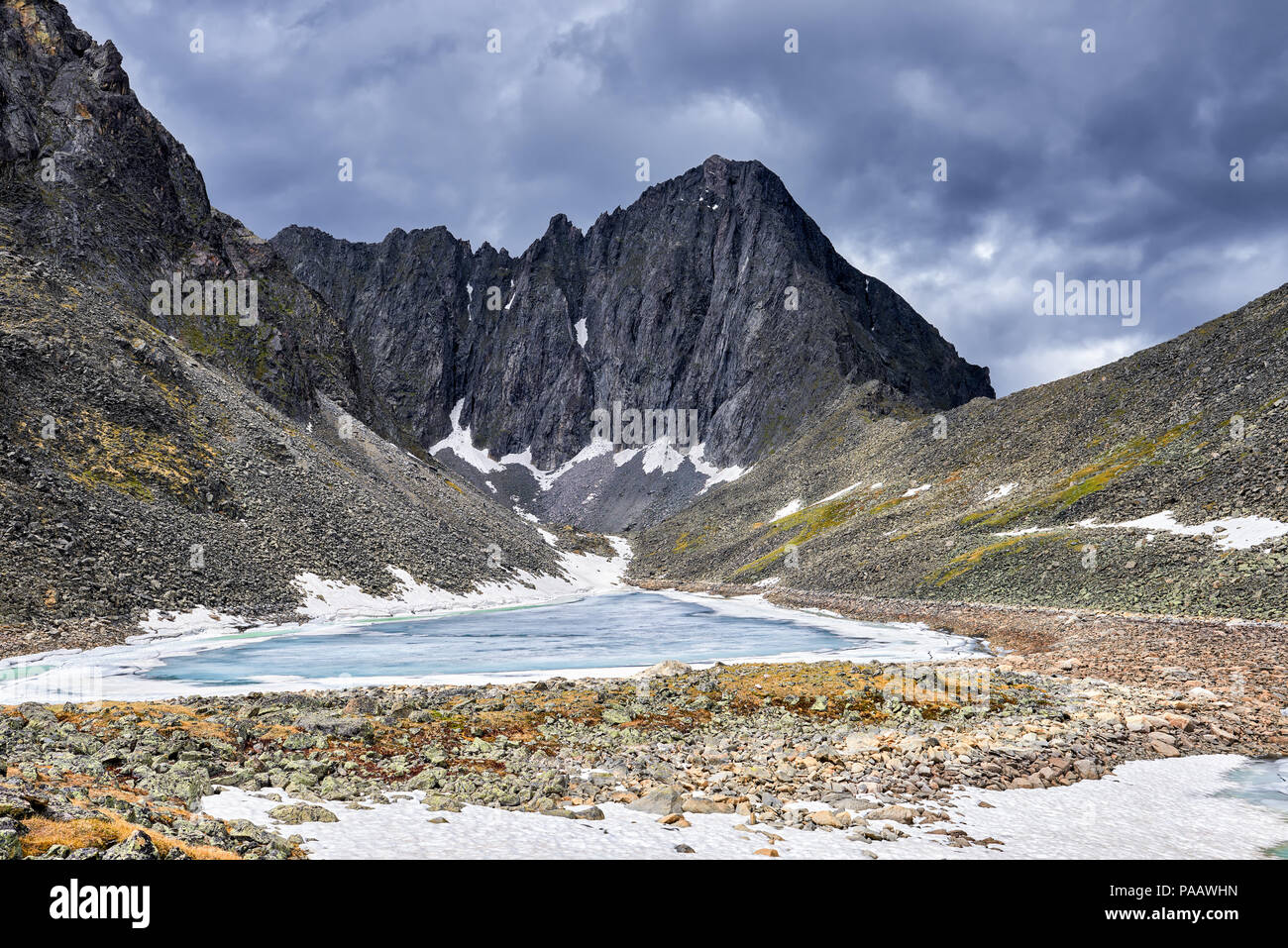 Frozen lake in mountain circus in front of peak. East Sayan. Russia ...