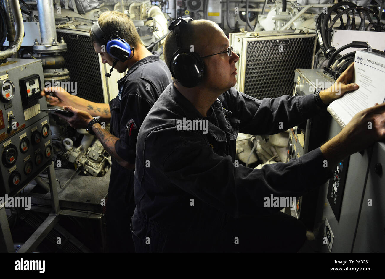 Crew members operate in the engine room of the Patrol Craft USS Shamal ...