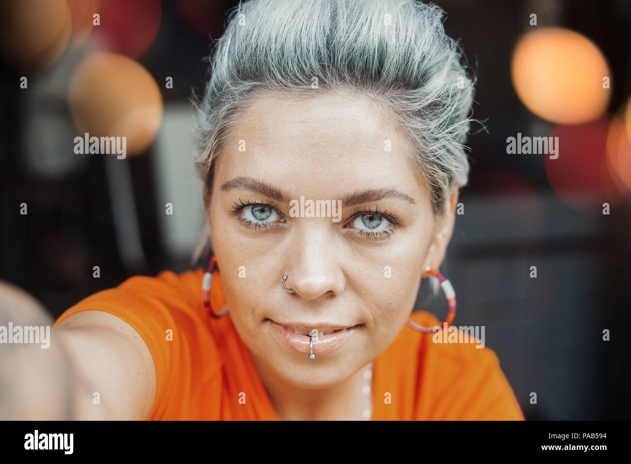 Attractive Pensive Blonde Girl In Orange T Shirt Making Selfie At Cafe