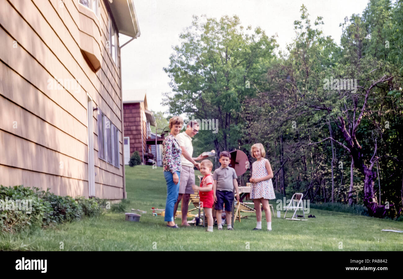 American family with young children having a BBQ in a back garden or ...